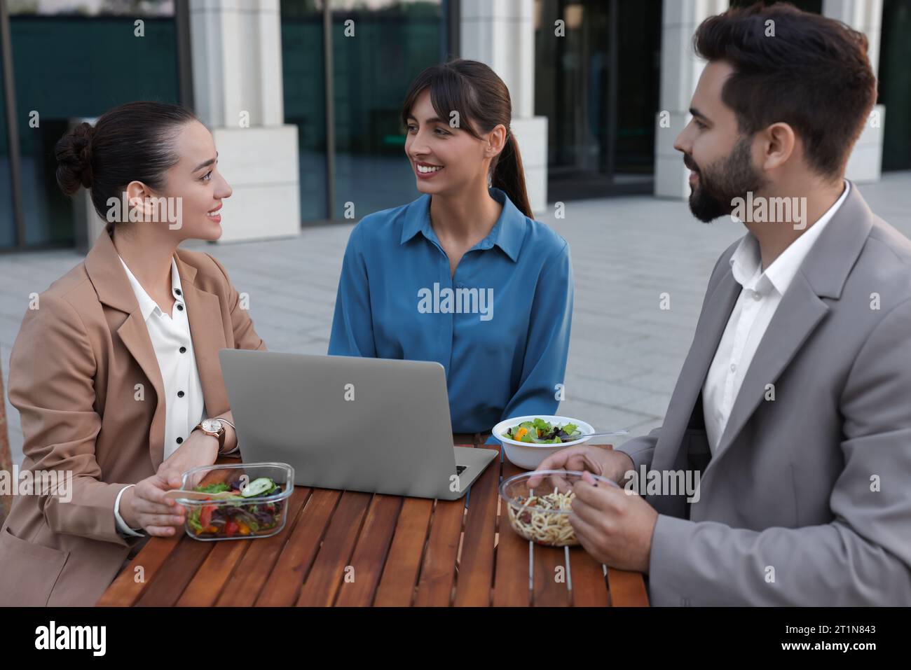 Business lunch. Happy colleagues with laptop spending time together at ...