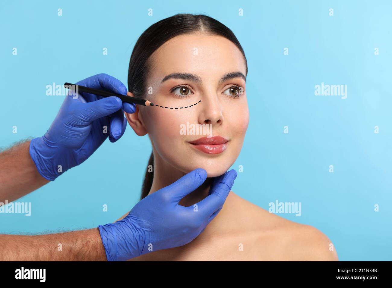 Woman preparing for cosmetic surgery, light blue background. Doctor ...