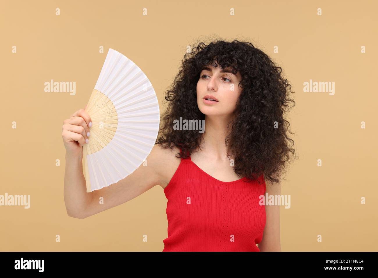 Woman with hand fan suffering from heat on beige background Stock Photo ...