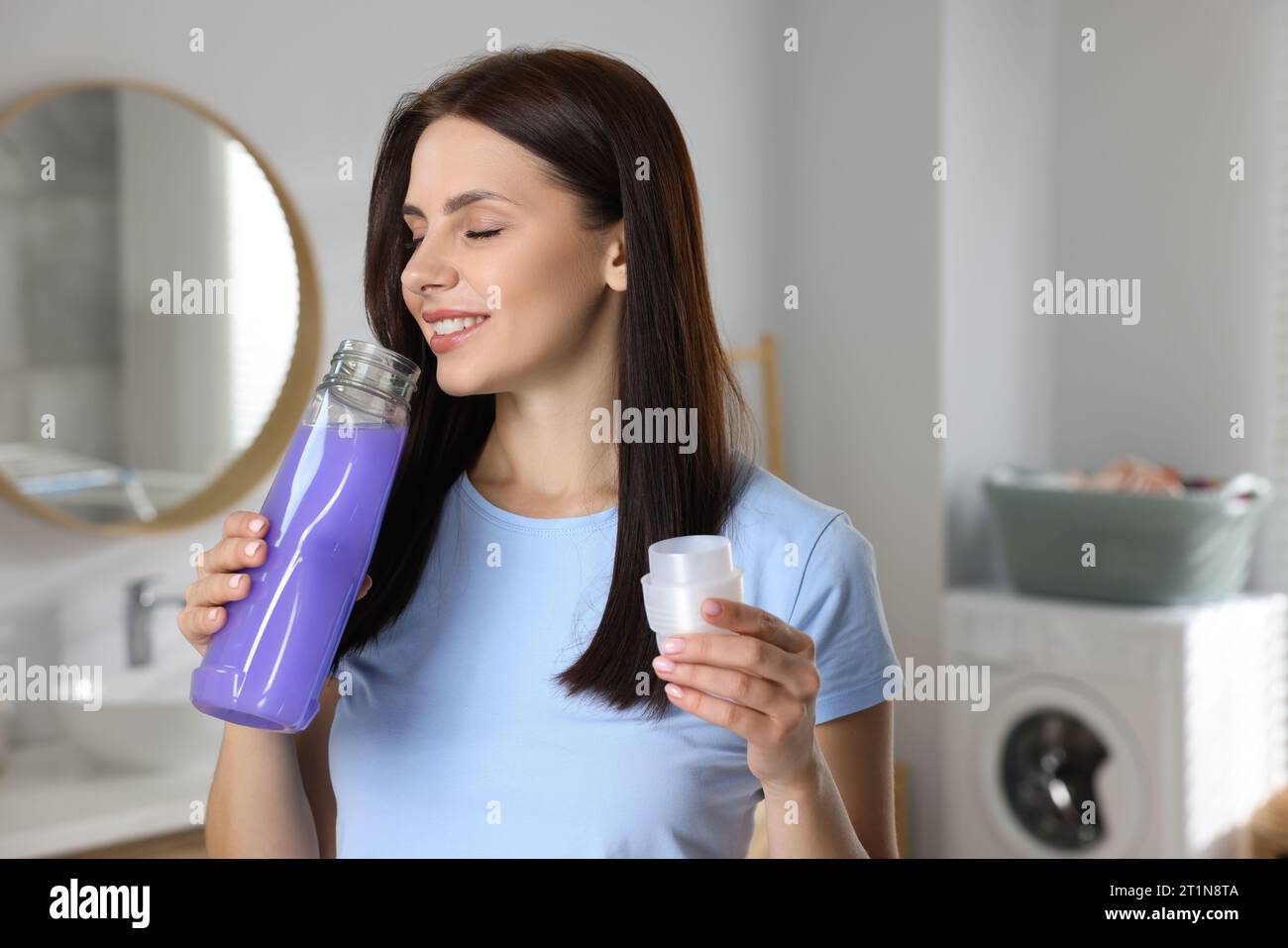 Woman smelling fabric softener in bathroom, space for text Stock Photo ...