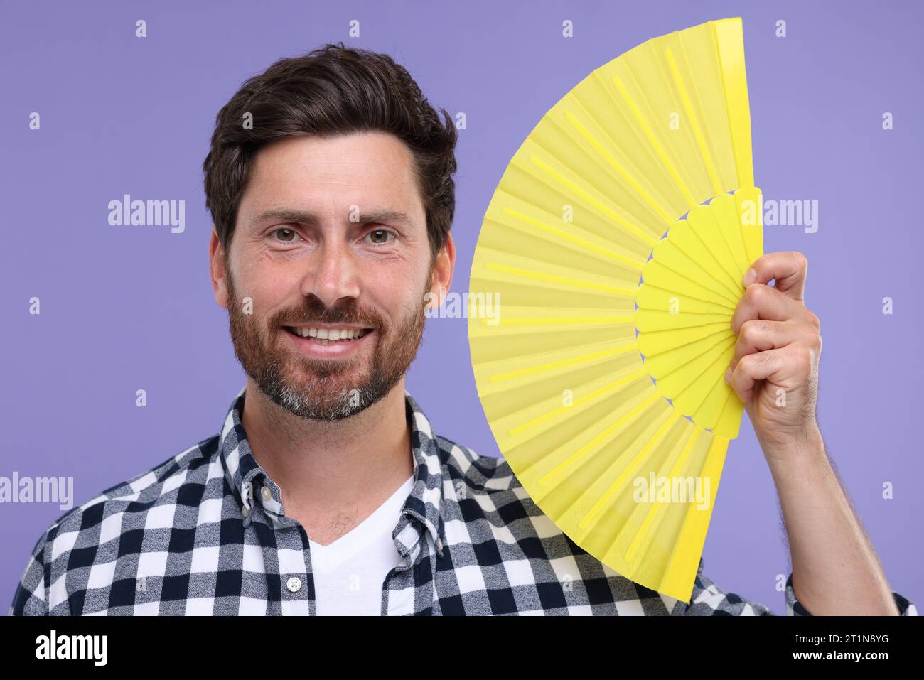 Happy man holding hand fan on purple background Stock Photo - Alamy