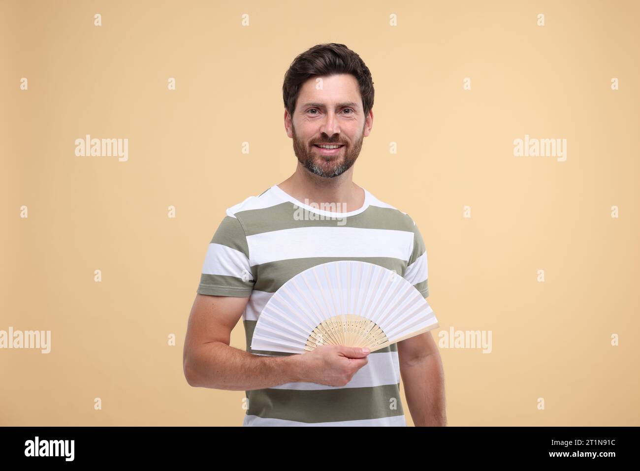 Happy man holding hand fan on beige background Stock Photo - Alamy
