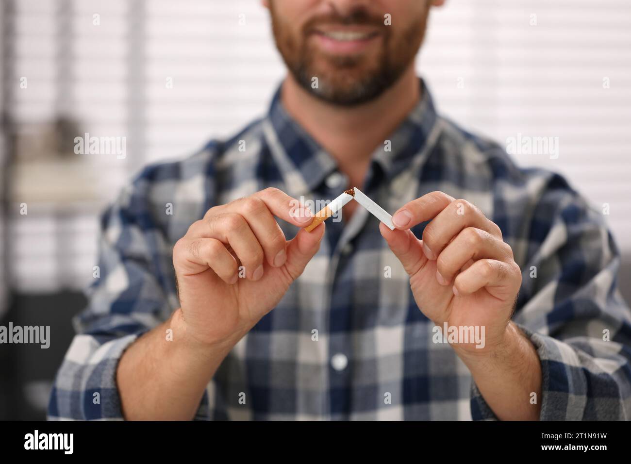 Stop smoking concept. Man breaking cigarette on blurred background ...