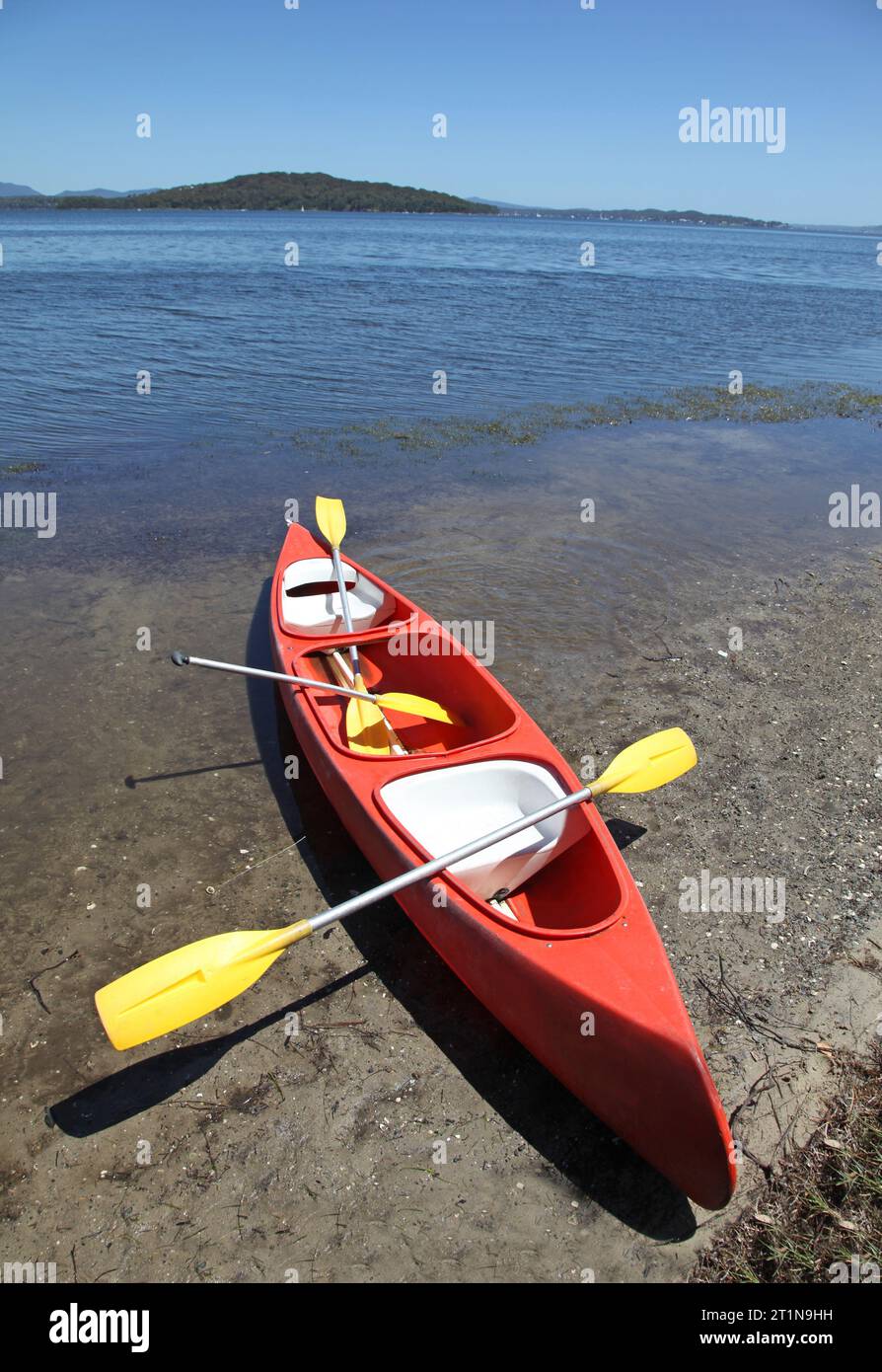 A bright orange canoe with yellow paddles Stock Photo - Alamy