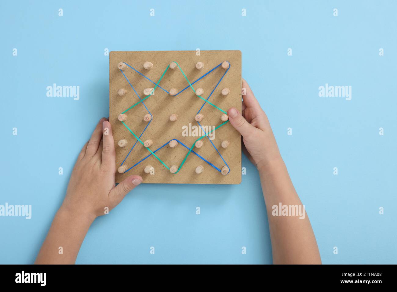 Motor skills development. Boy with geoboard and rubber bands at light ...