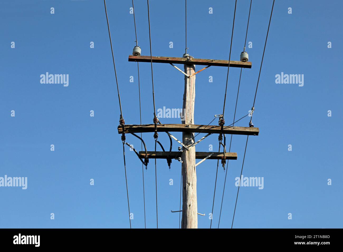 An old power pole carrying 11kV and LV with blue sky background Stock ...