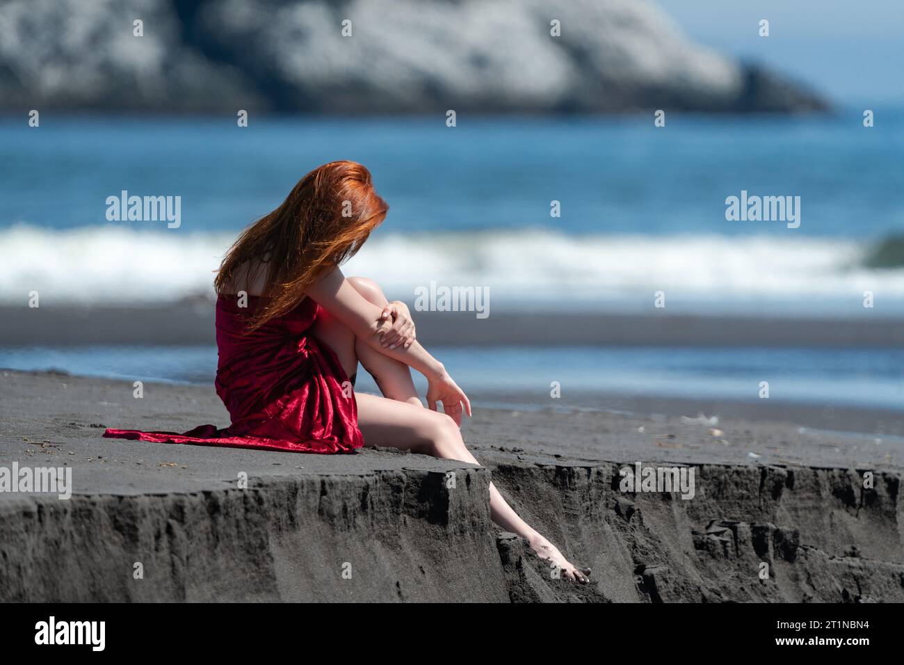 Unrecognizable woman in red dress with raised hem sitting on sandy ...