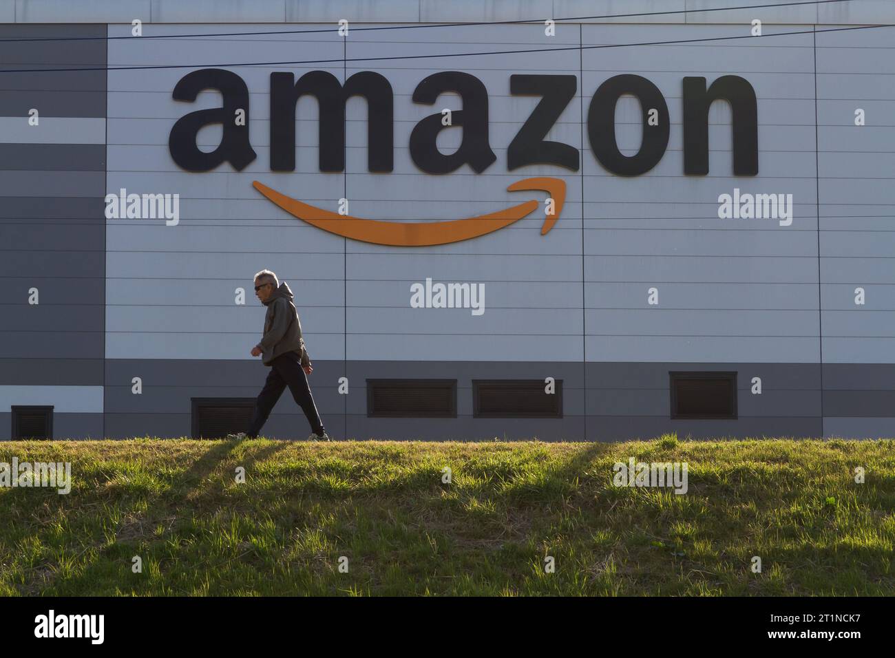 A man walks past and Amazon warehouse in Kawasaki, Kanagawa, Japan ...