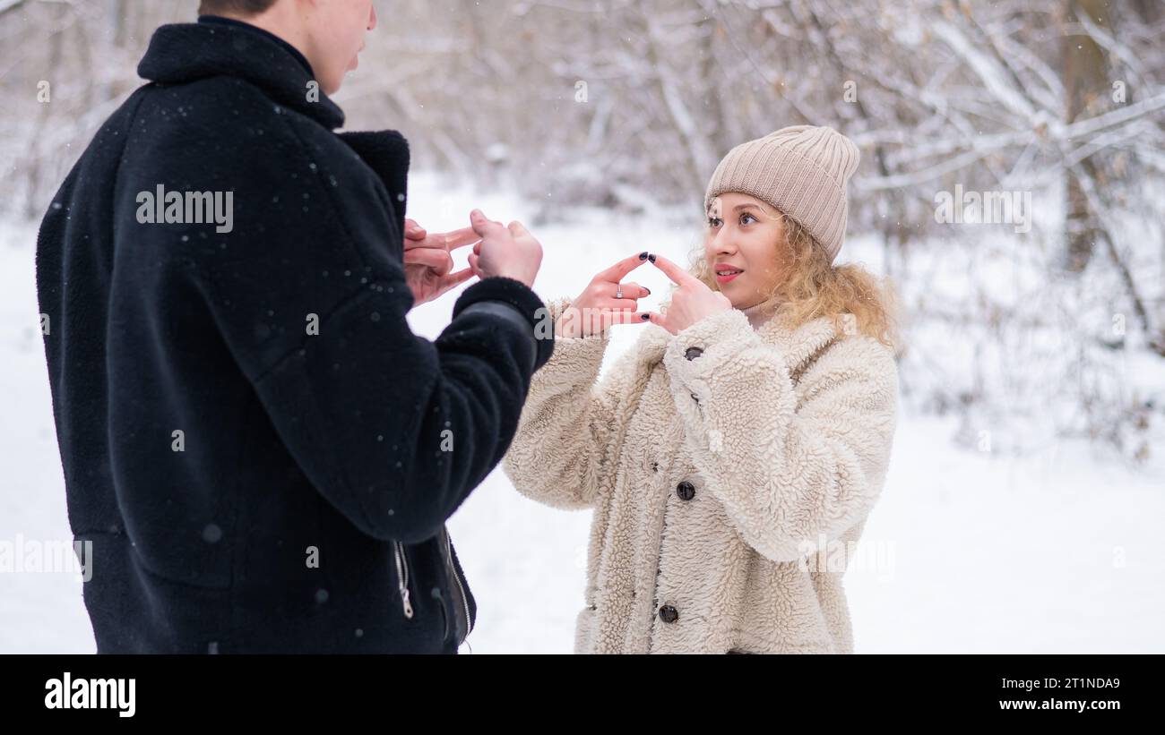 A young couple walks in the winter in the forest. Deaf Guy and a girl ...
