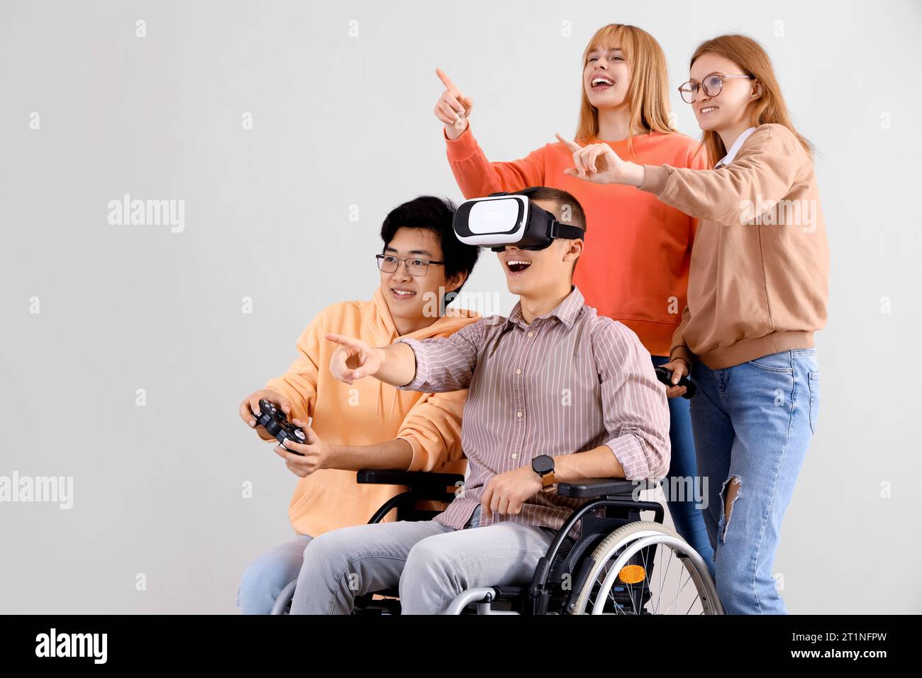 Group of teenagers with boy in wheelchair playing video game on light ...