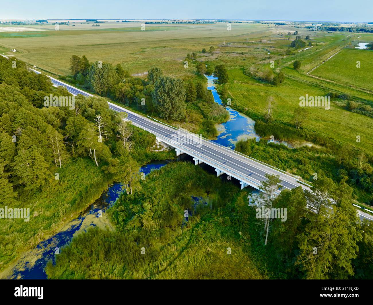 Road bridge over river surrounded by green trees and fields Stock Photo ...