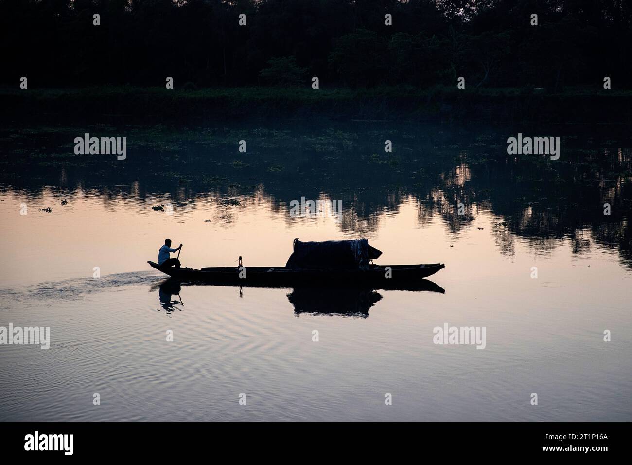 Silhouette of a local fisherman sitting on back of dugout canoe with ...