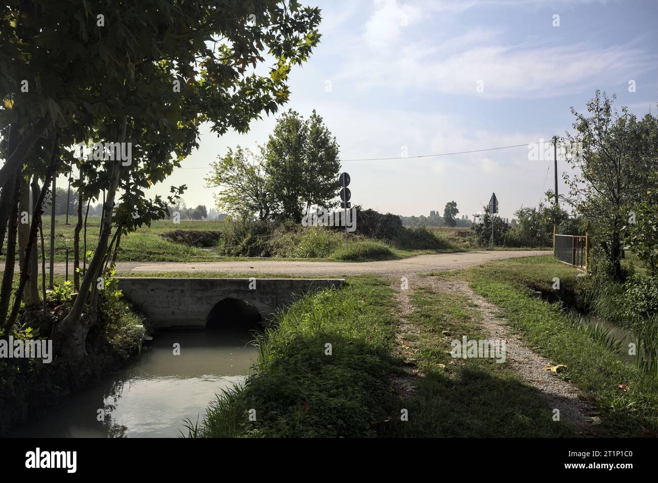 Crossing between a path and a gravel road next to a trench with water ...