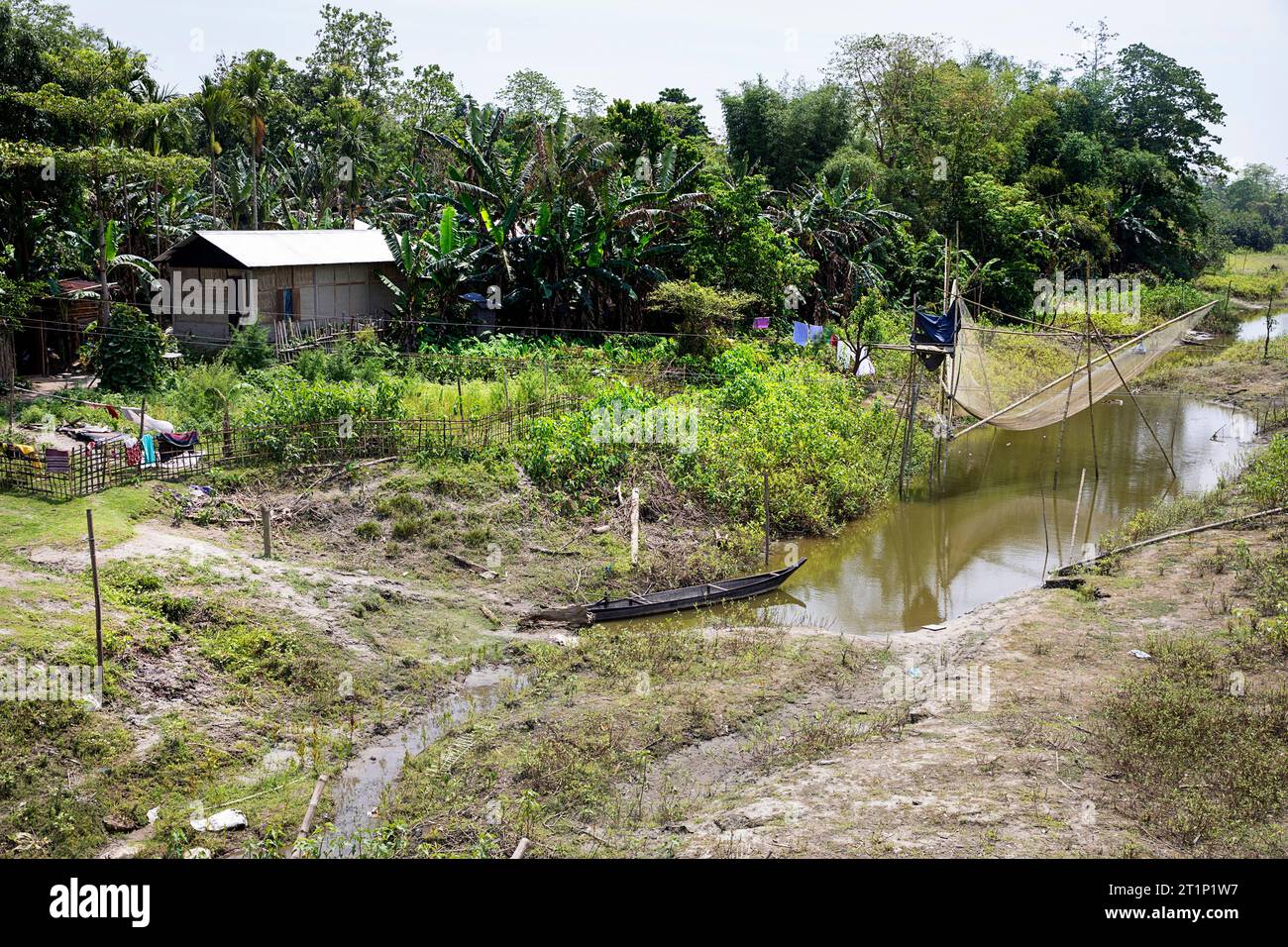Traditional small bamboo house and traditional fishing net on a small river in majuli island in ...