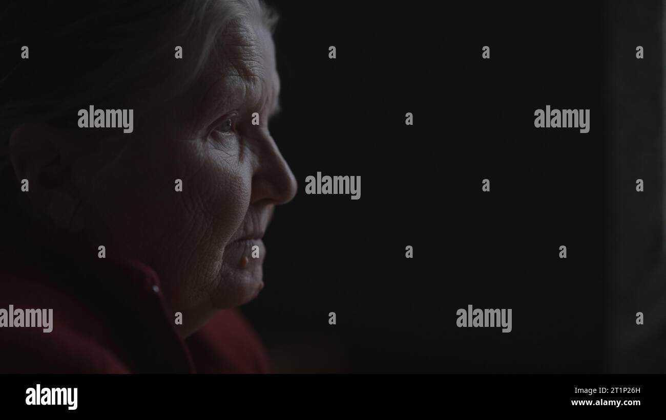 shot of old woman sitting near window and thinking about something ...