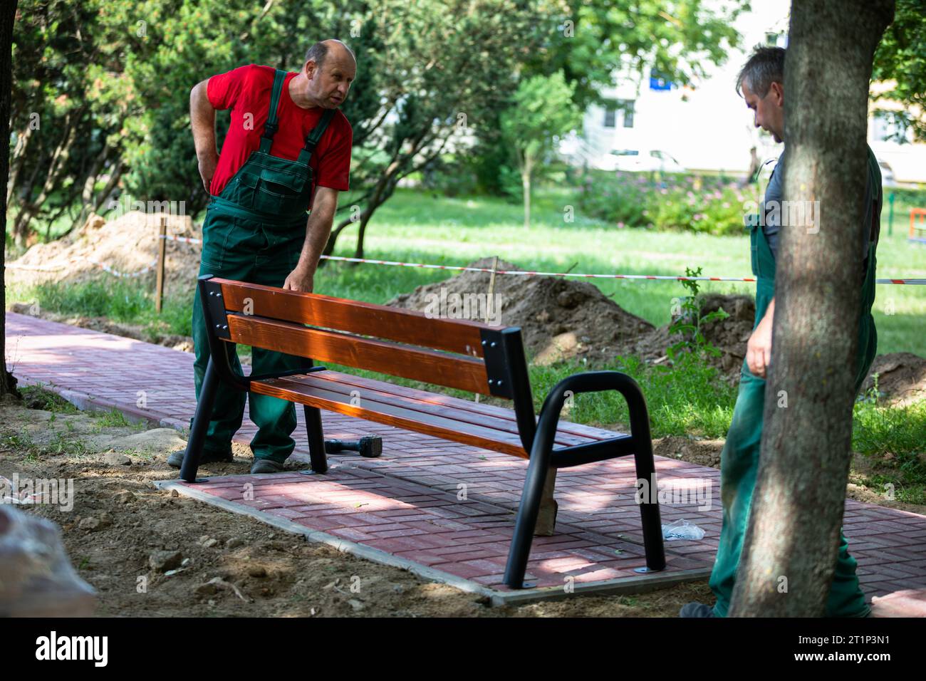Physical workers set up a park bench at a designated spot in a city ...