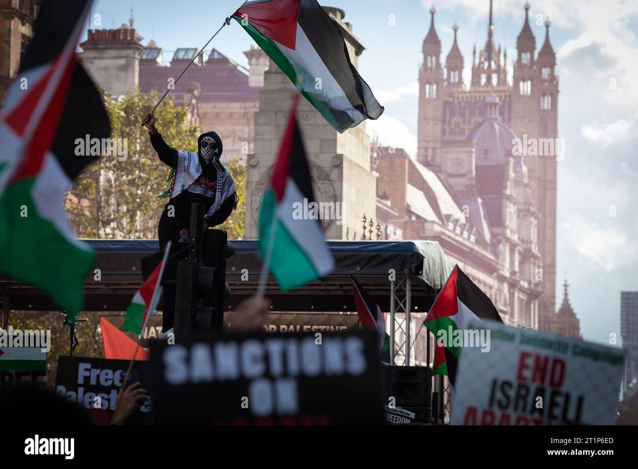 London, UK. 14th Oct, 2023. A protester mounts a traffic light outside ...