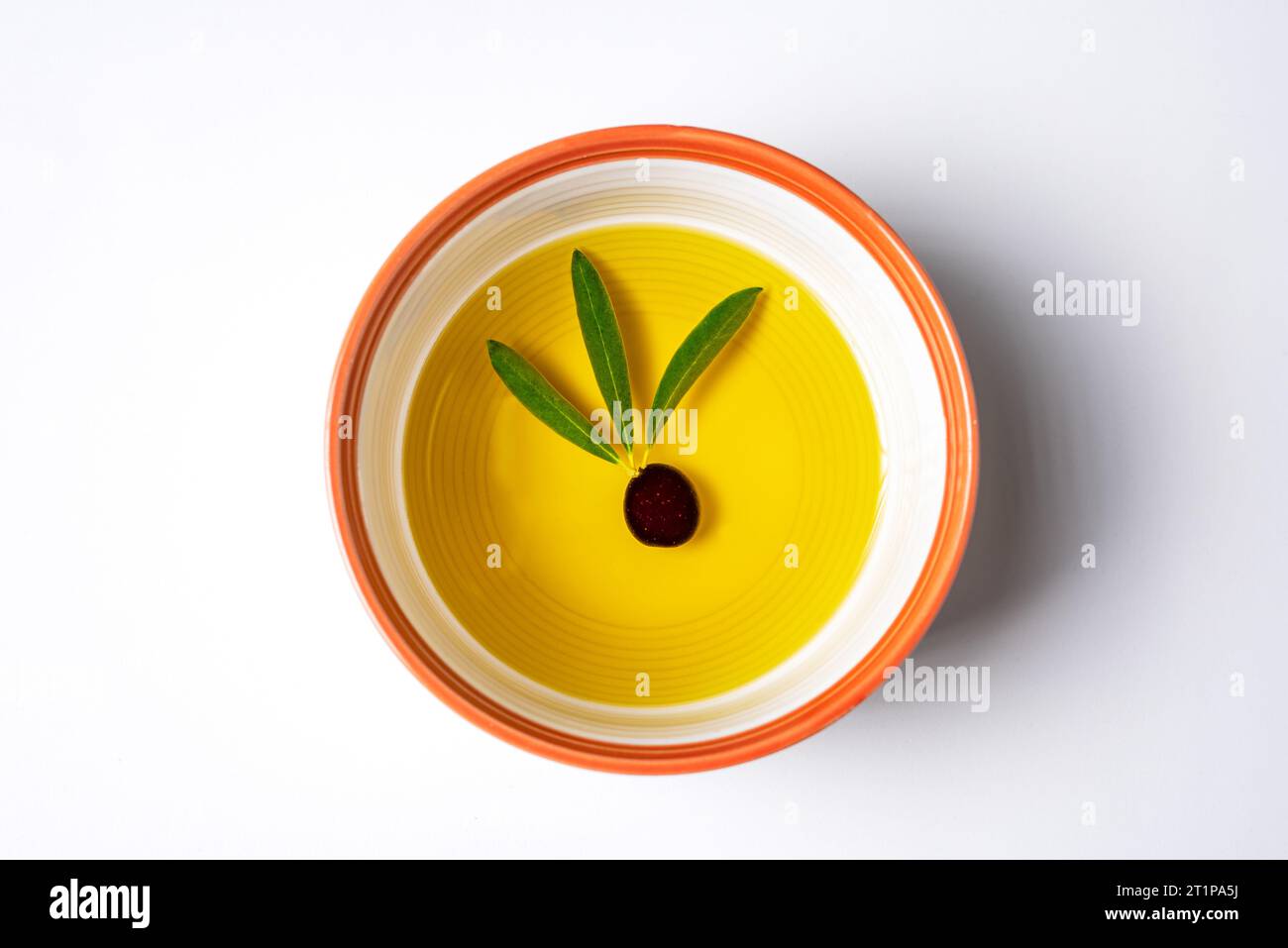 Bowl with virgin olive oil with an olive inside with three olive leaves ...