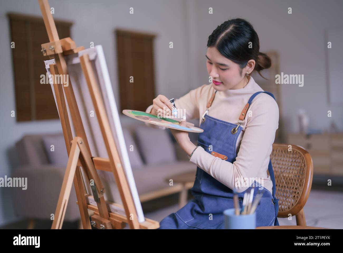 Young asian female artist squeeze color out of tube on color palette ...