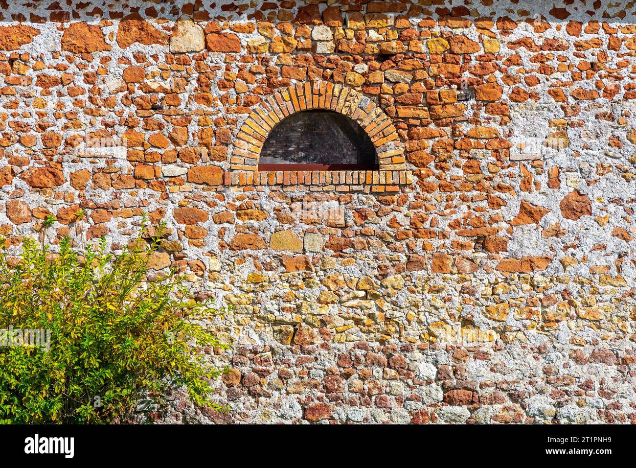 Half-round window in house wall built with from iron-rich sandstone ...
