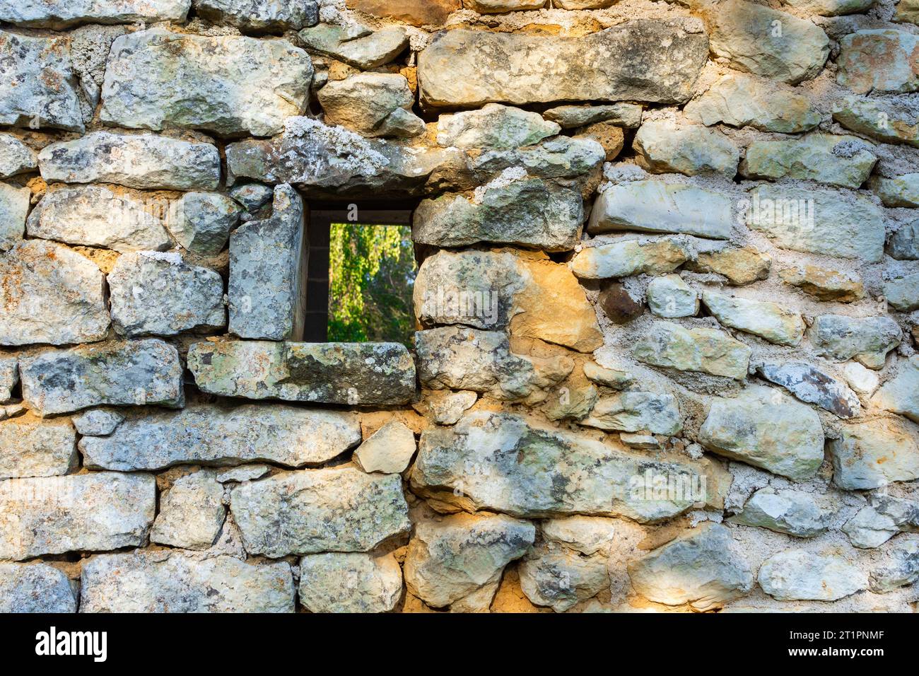 Random stone wall with small square window opening in farm building ...
