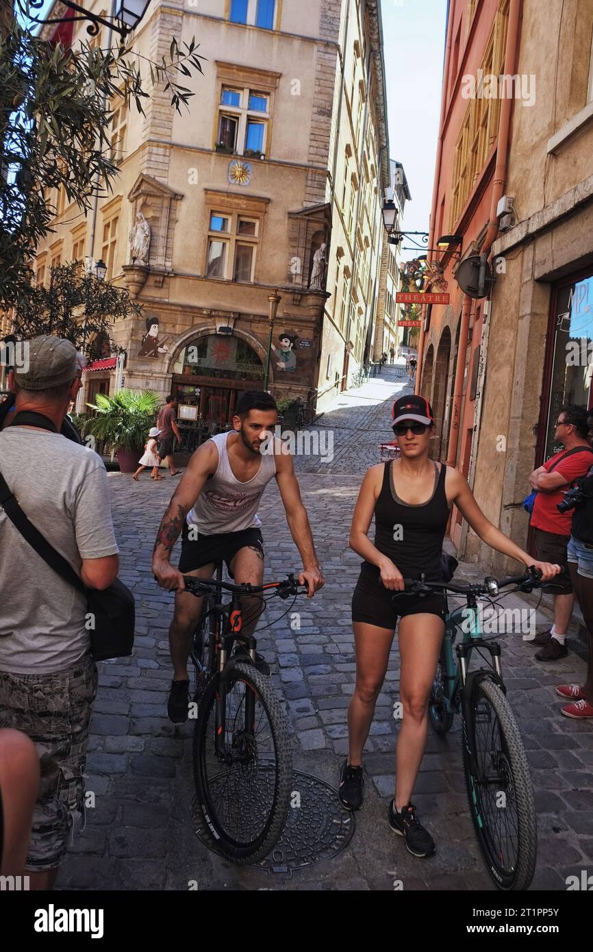 Two cyclists one riding the other walking their bike along a ...