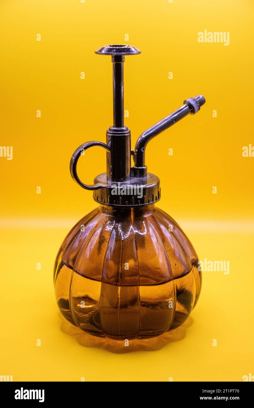 An old leaf spraying device filled with water on a yellow background ...