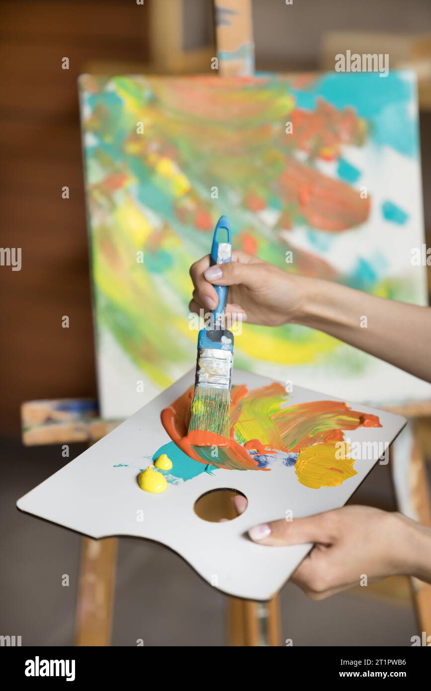 Painter holding palette and paintbrush, mixing acrylic paints colors ...