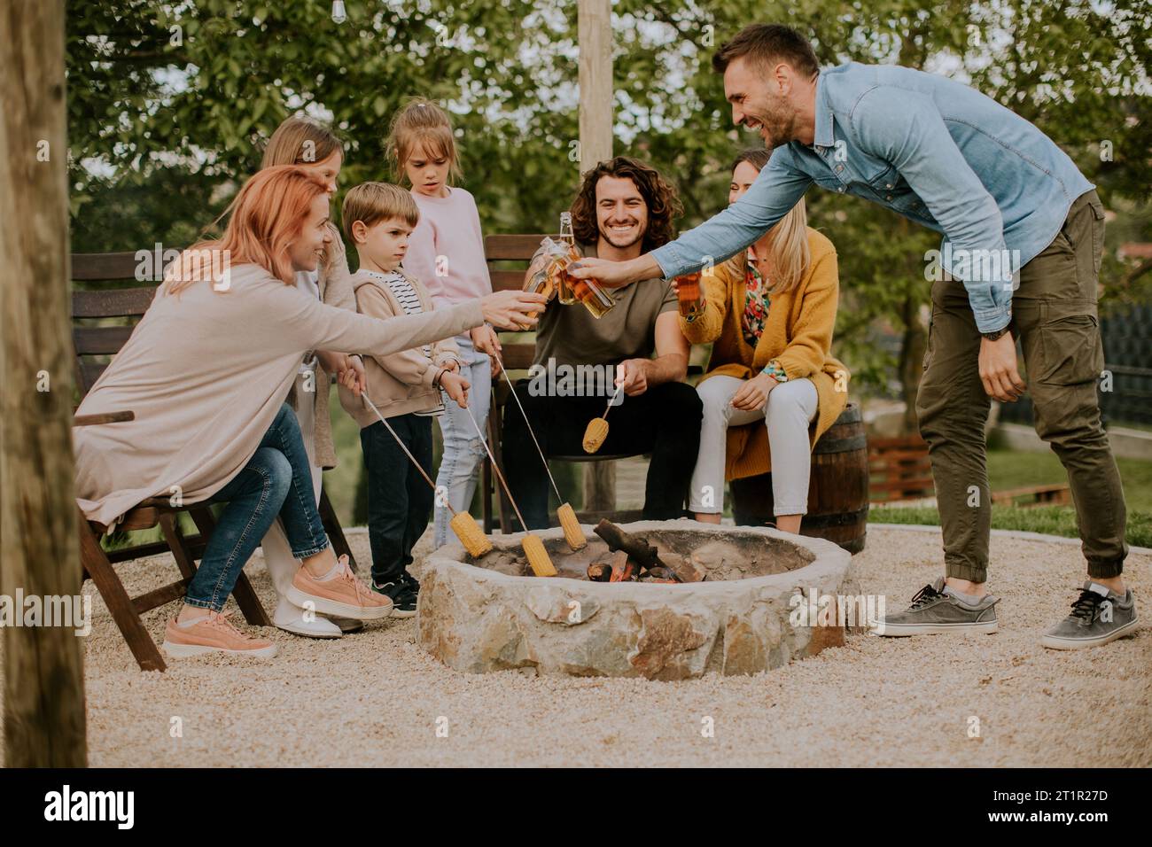 Group of friends having good time and baking corns in the house ...
