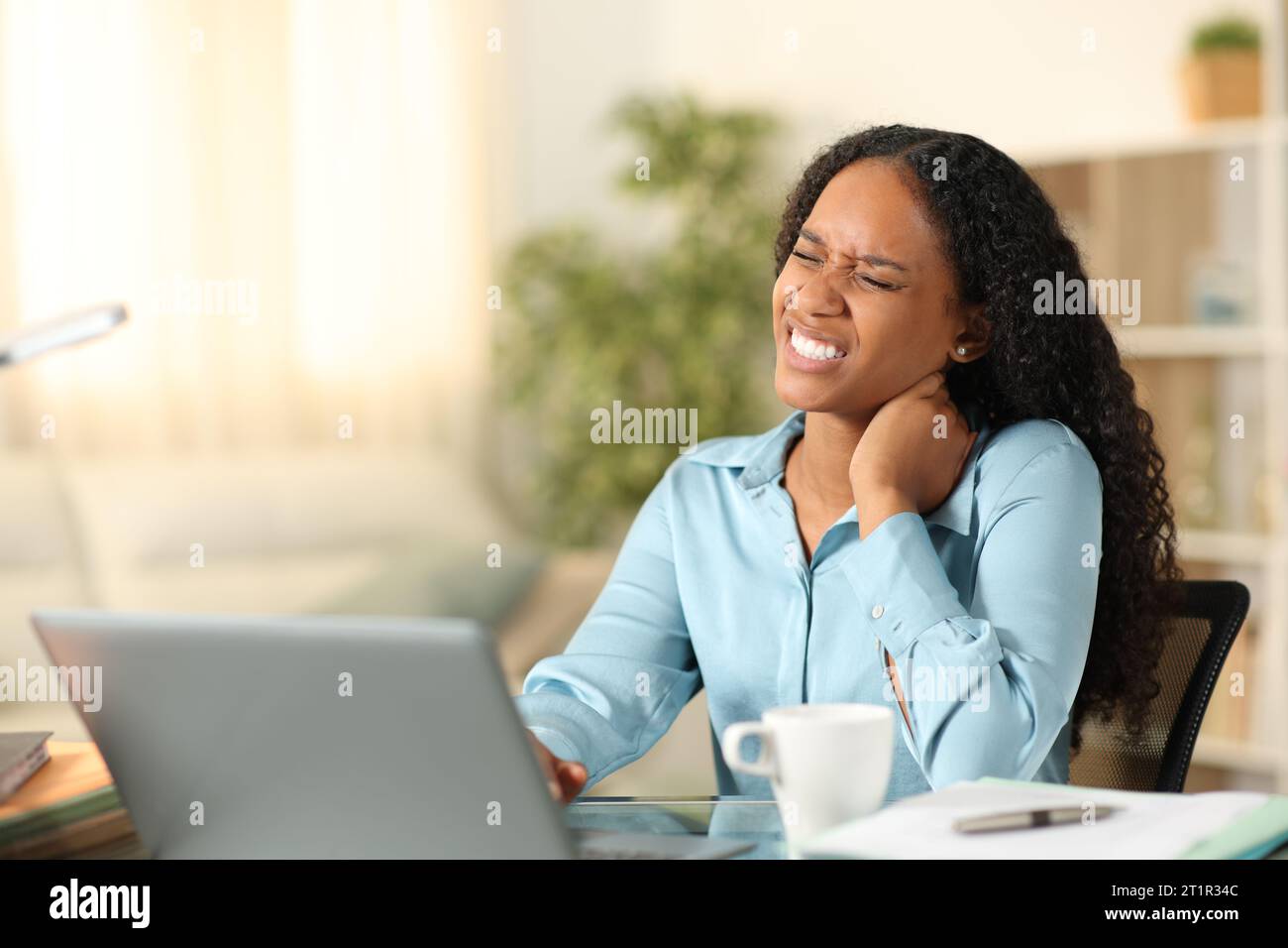 Black teleworker suffering neck ache sitting on a chair at home Stock ...