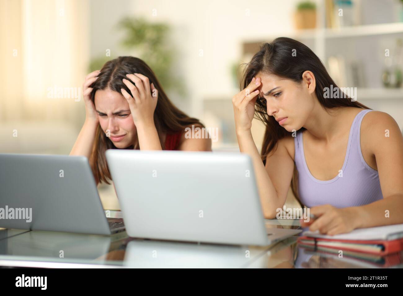 Sad students checking bad grades on laptops sitting at home Stock Photo ...
