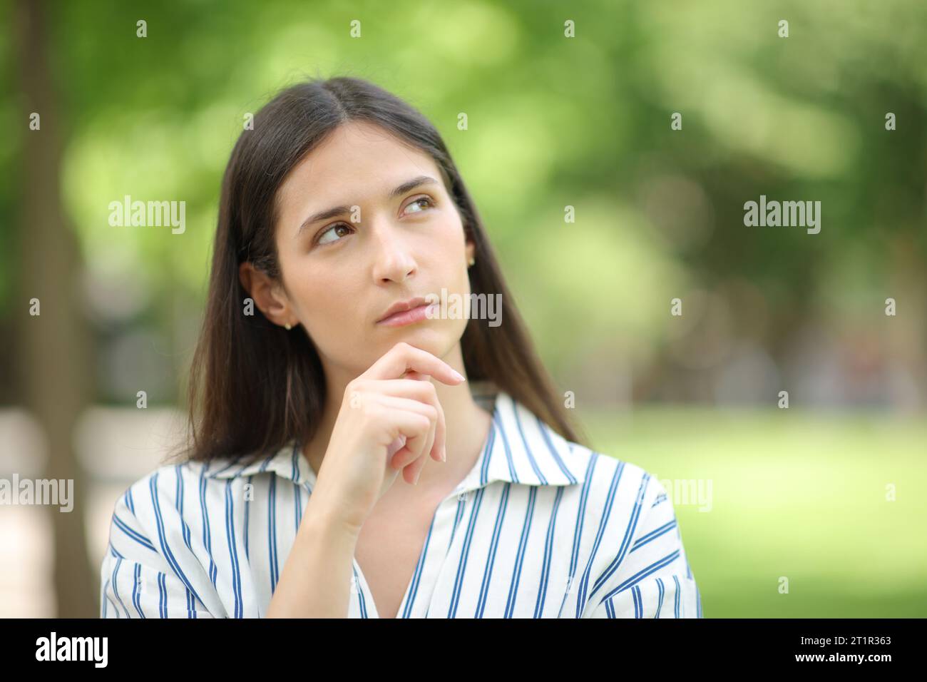 Front view portrait of a pensive woman looking at side on green ...