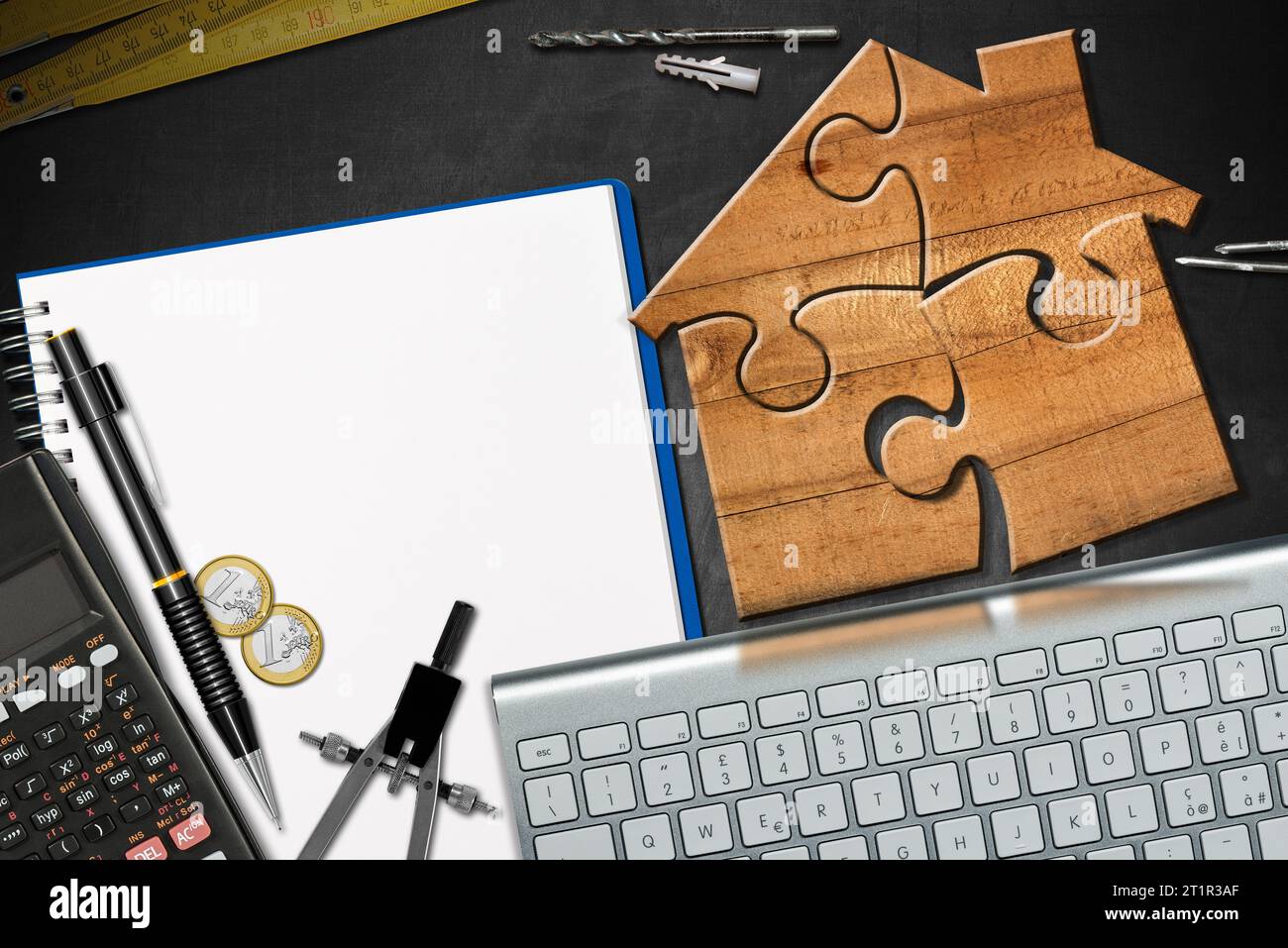 Wooden house made of jigsaw puzzle pieces on a desk with empty notebook ...