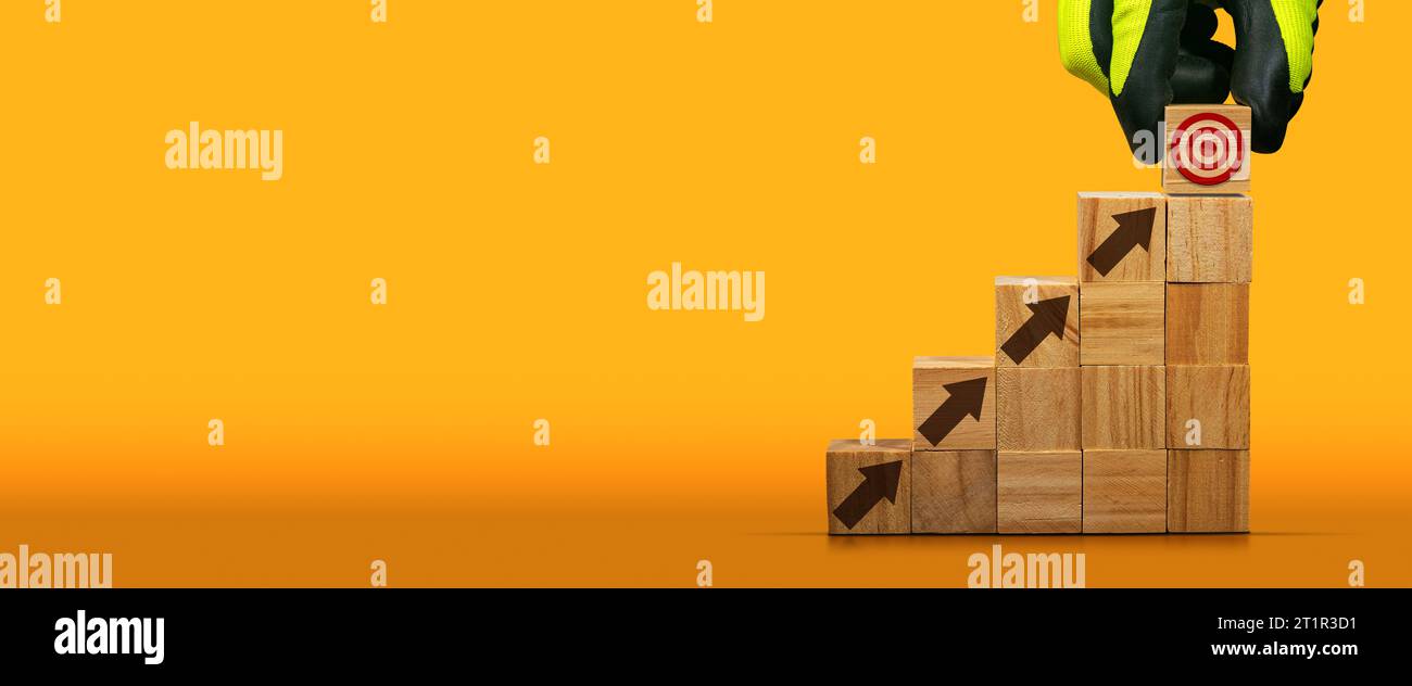 Gloved hand arranging wood blocks as step stair with a target symbol on ...