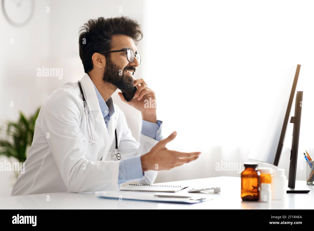 Indian Doctor Juggling Computer Work and Phone Call Stock Photo - Alamy