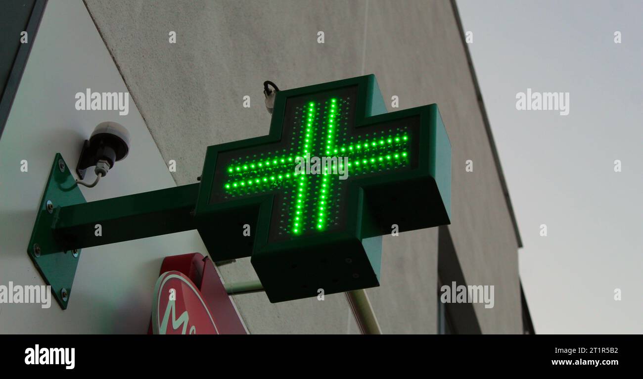 A photo of a green pharmacy cross sign attached to the exterior of a ...