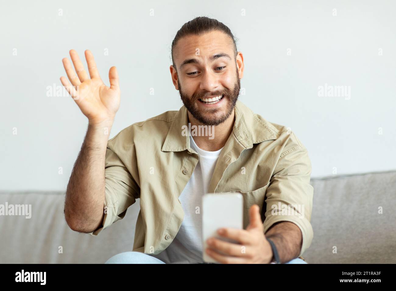 Positive guy waving hand at phone, having talk with friends Stock Photo ...