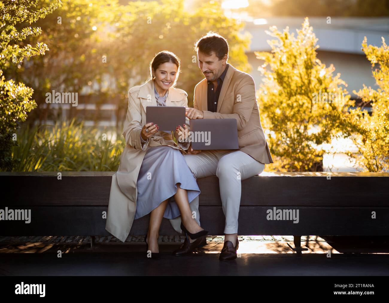 Team Collaborating on Gadgets Amidst City Life at Park Stock Photo - Alamy