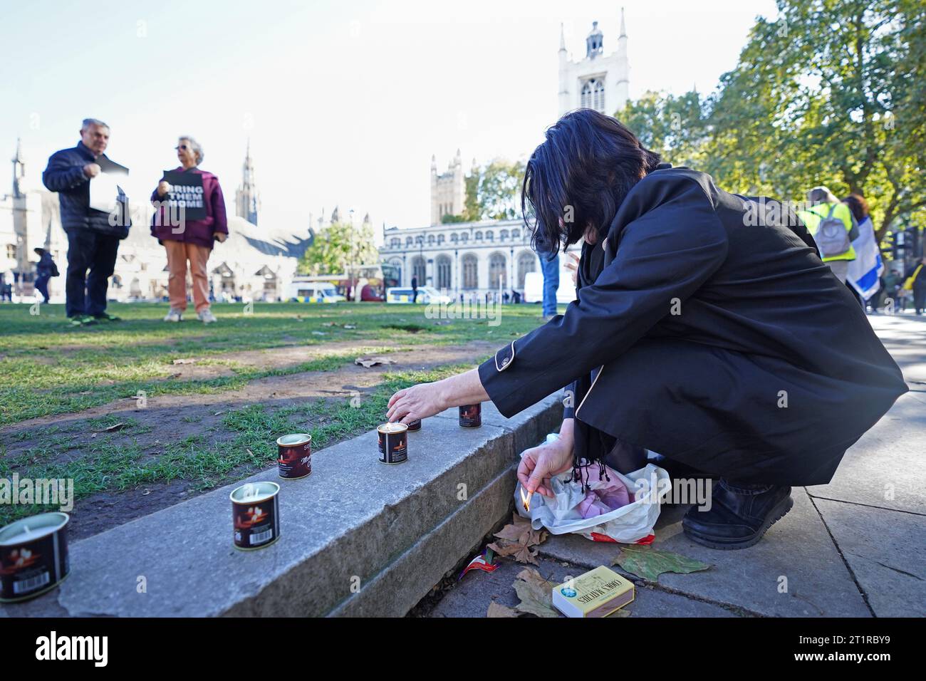A woman lights a candle a vigil at Parliament Square in London, for ...