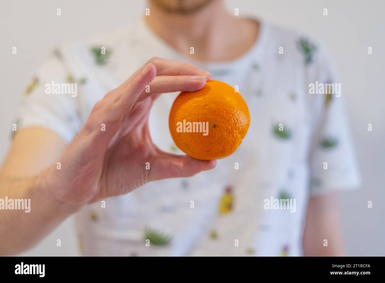 man holding an orange in front of him Stock Photo - Alamy