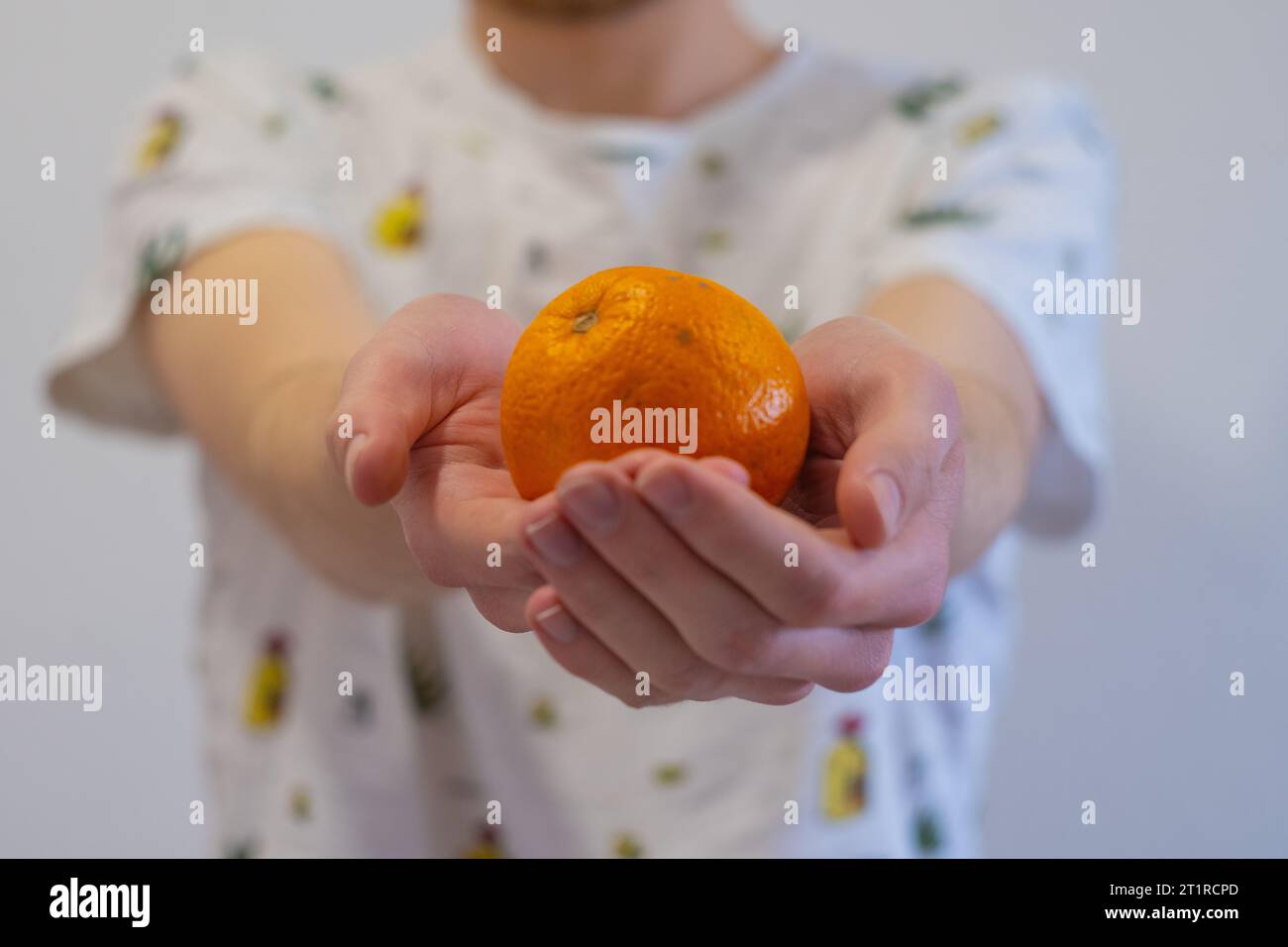 man holding an orange in front of him Stock Photo - Alamy
