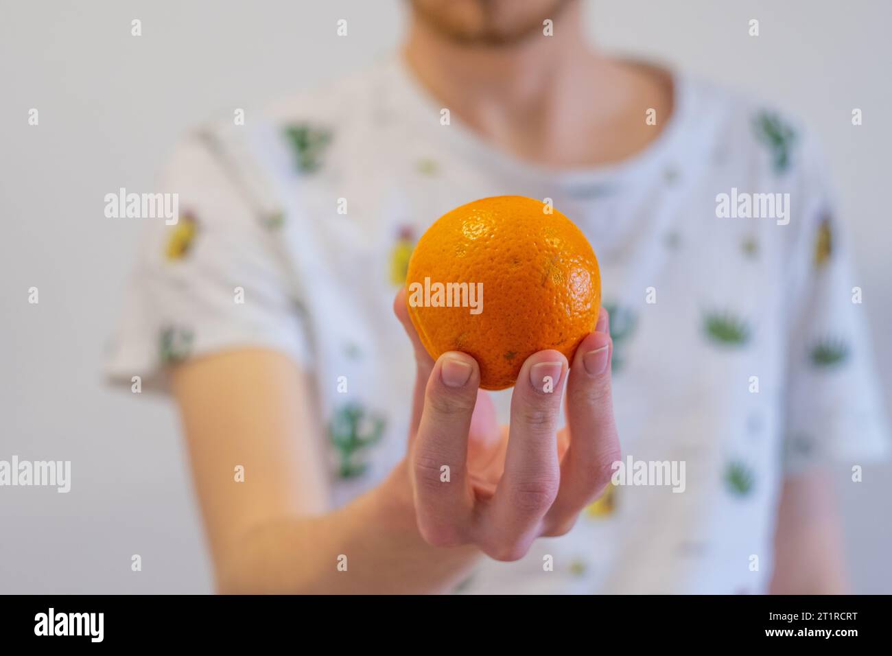 man holding an orange in front of him Stock Photo - Alamy