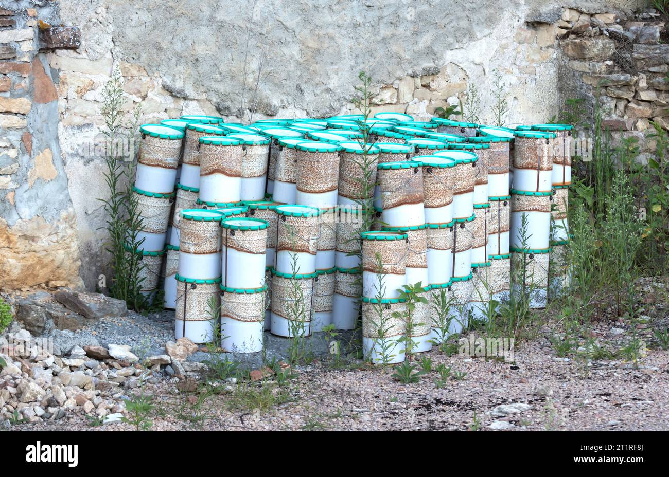 Abandoned rusty cans, stacked against an old wall, France Stock Photo ...