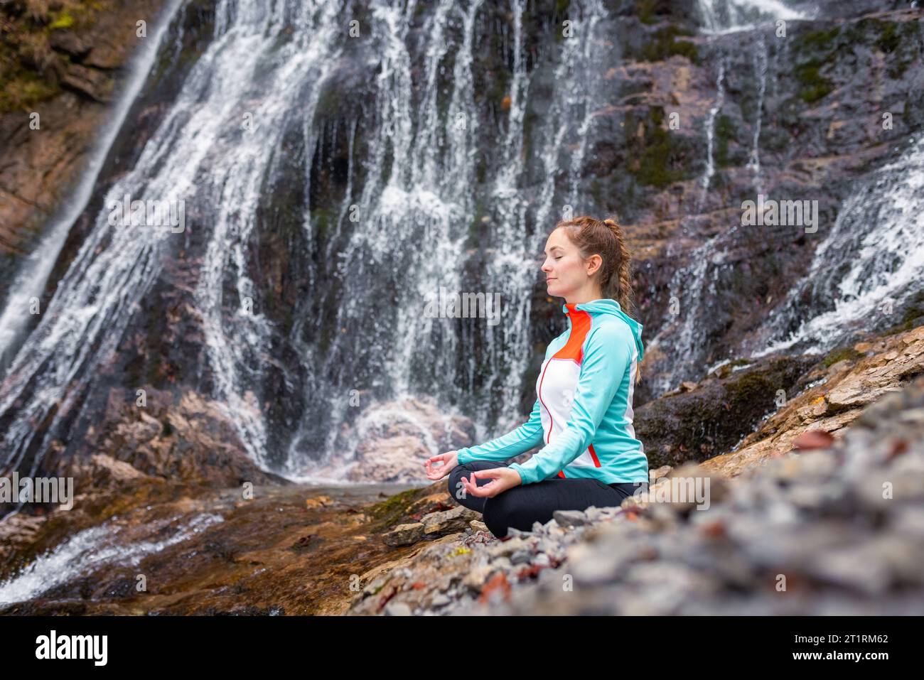 Fit young woman practicing yoga in beautiful waterfall scenery ...