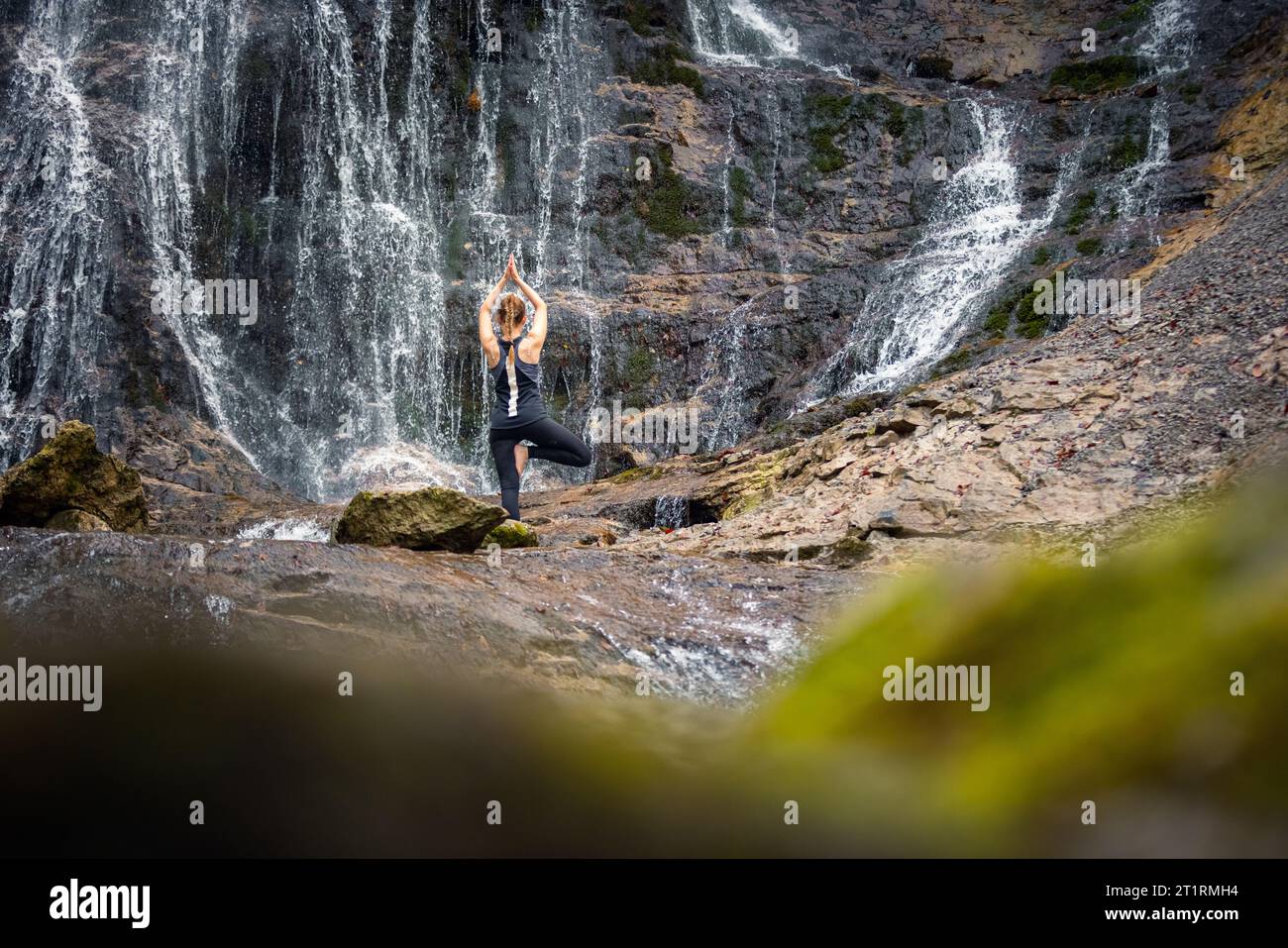 Fit young woman practicing yoga in beautiful waterfall scenery ...