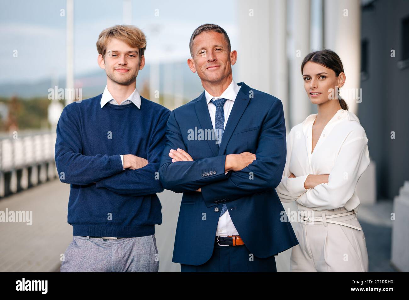 Three business professionals standing in front of a modern office ...
