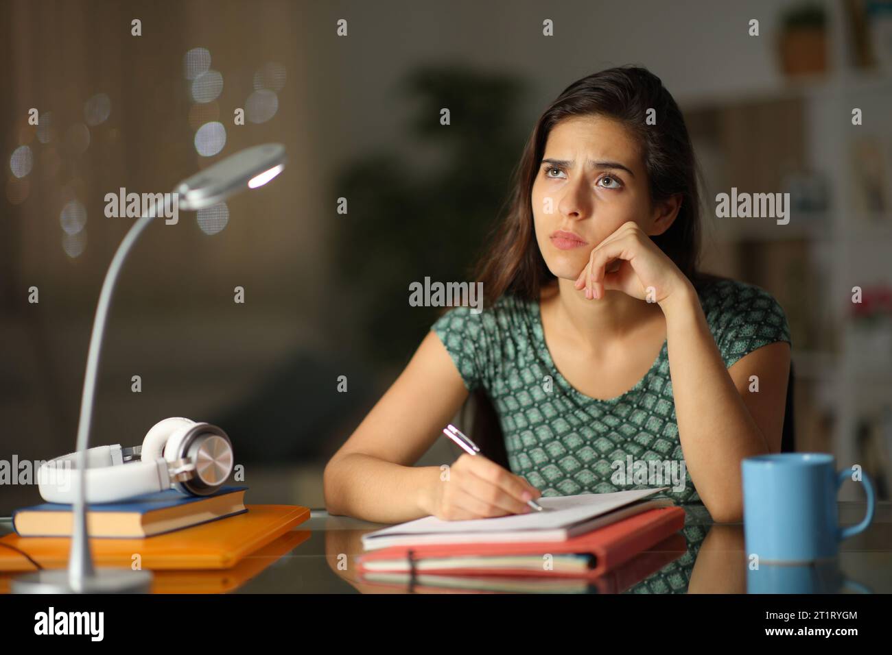 Worried student thinking trying to write a work in the night at home ...