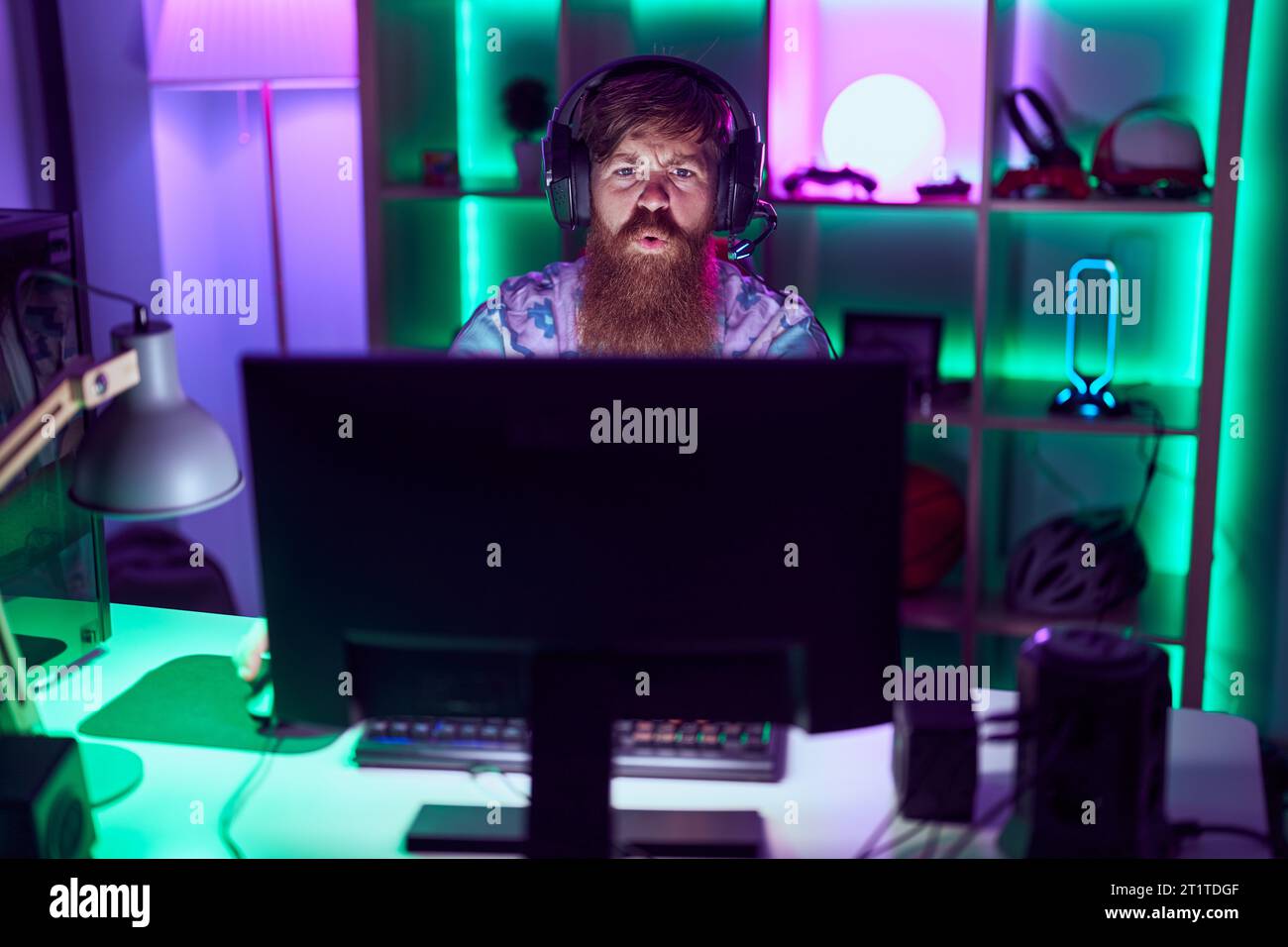 Young redhead man streamer playing video game using computer at gaming ...