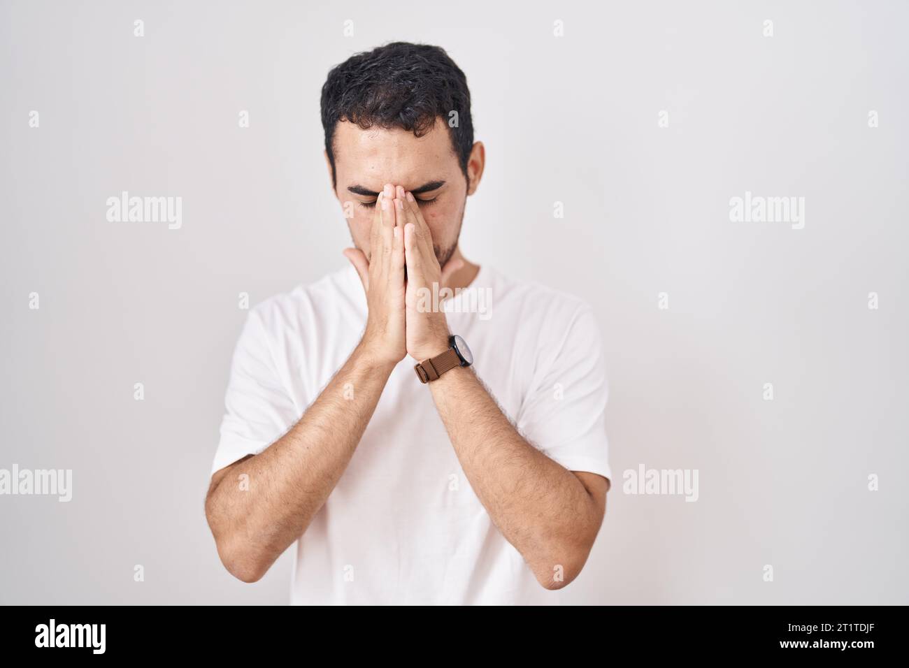 Handsome hispanic man standing over white background with sad ...