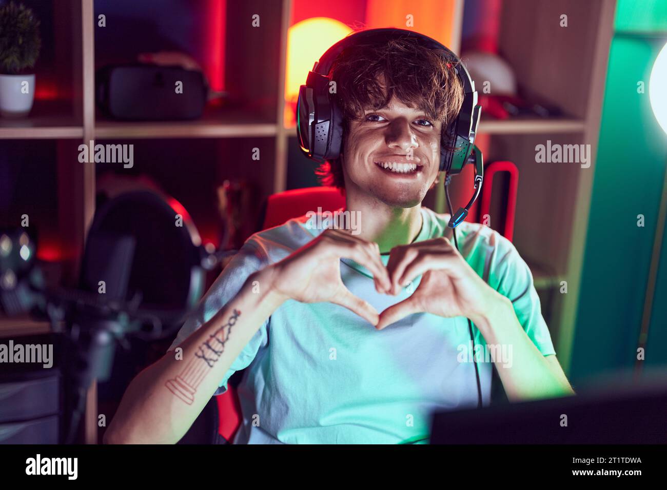 Young blond man streamer smiling confident doing heart symbol with ...